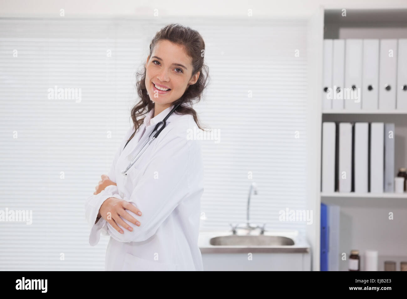 Smiling brunette doctor standing alone Stock Photo - Alamy