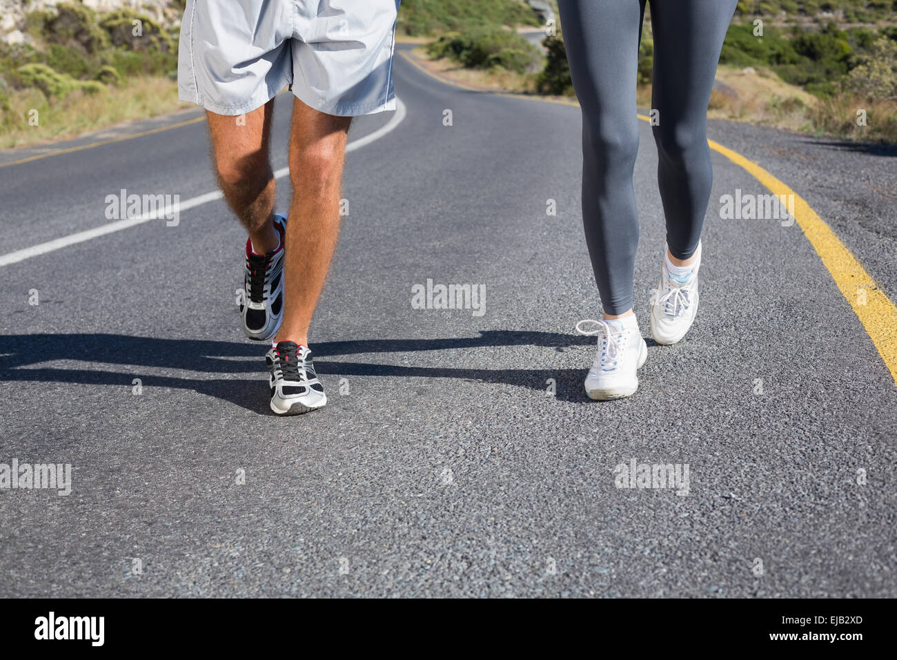 Fit couple running together up a road Stock Photo - Alamy