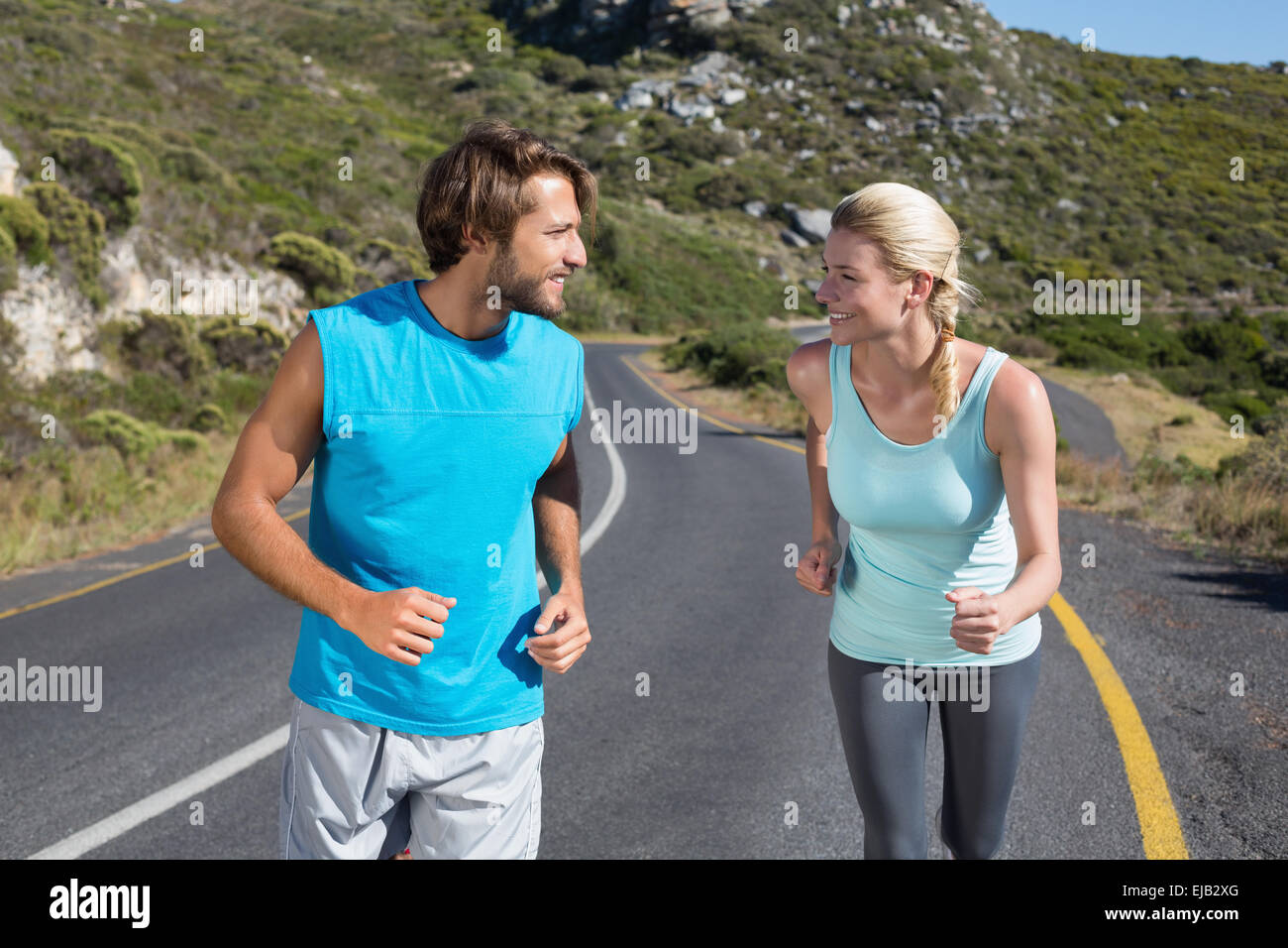 Fit couple running together up a road Stock Photo - Alamy