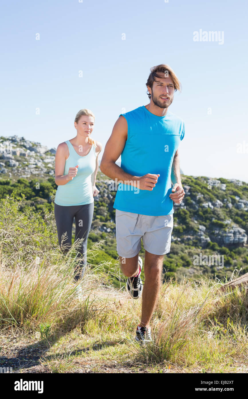 Fit couple jogging through countryside Stock Photo - Alamy