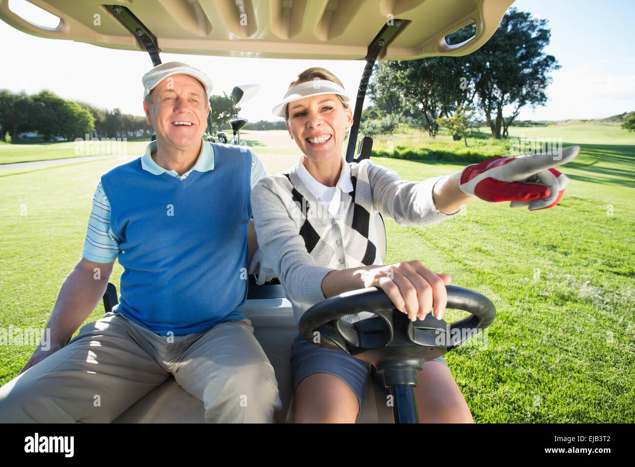 Happy golfing couple sitting in golf buggy Stock Photo - Alamy