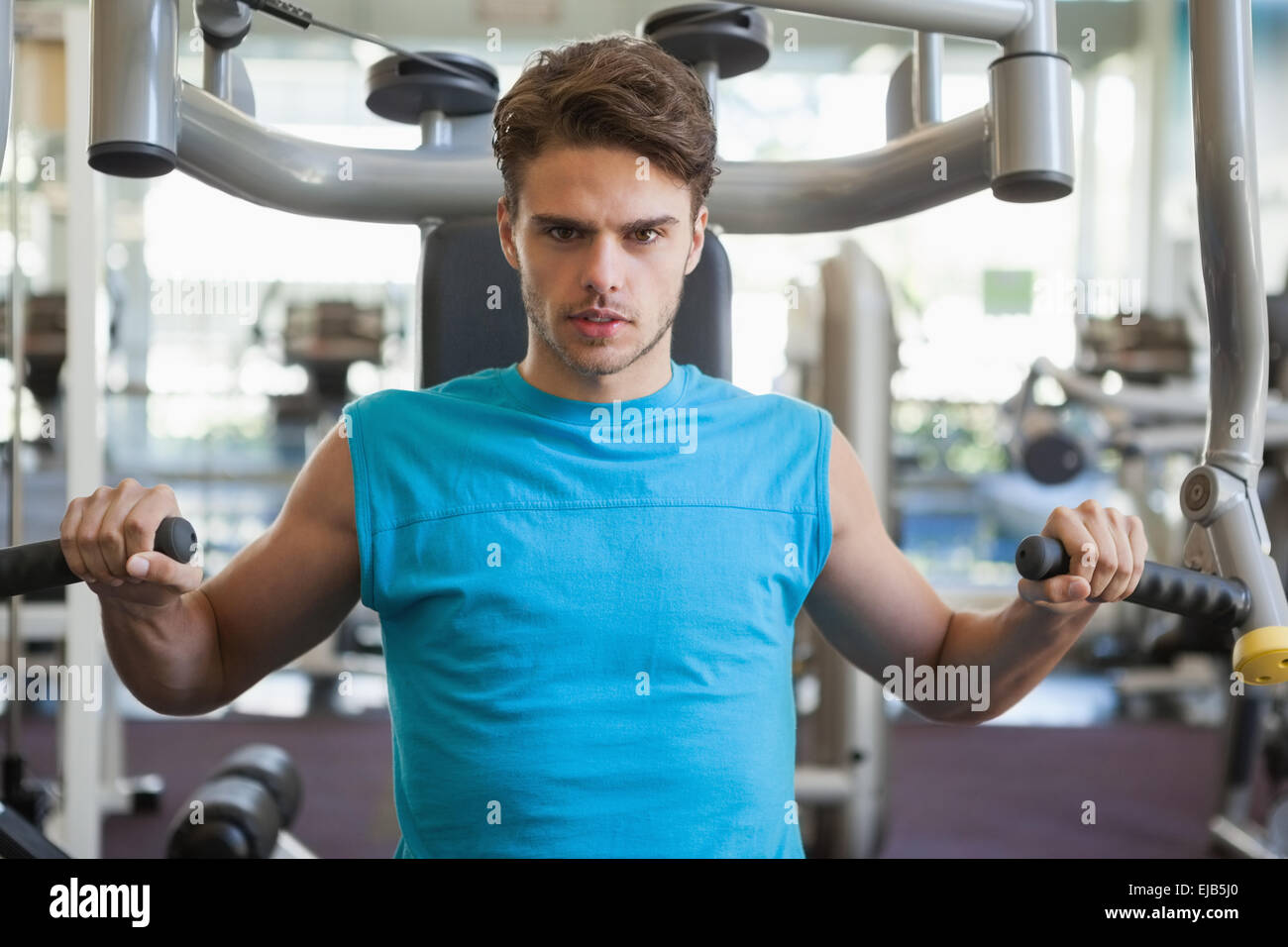 Focused man using weights machine for arms Stock Photo - Alamy