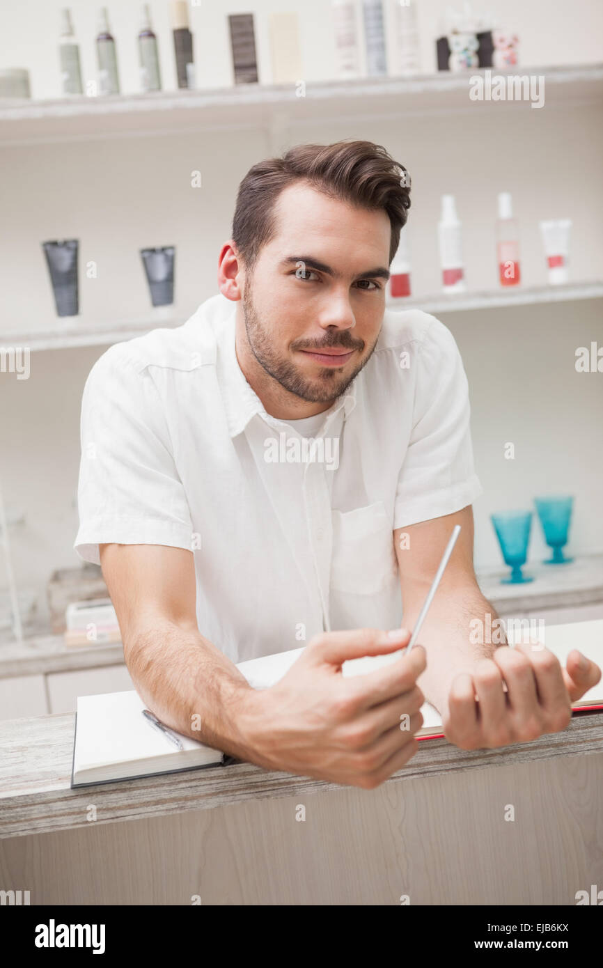 Smiling salon worker with stock book Stock Photo - Alamy