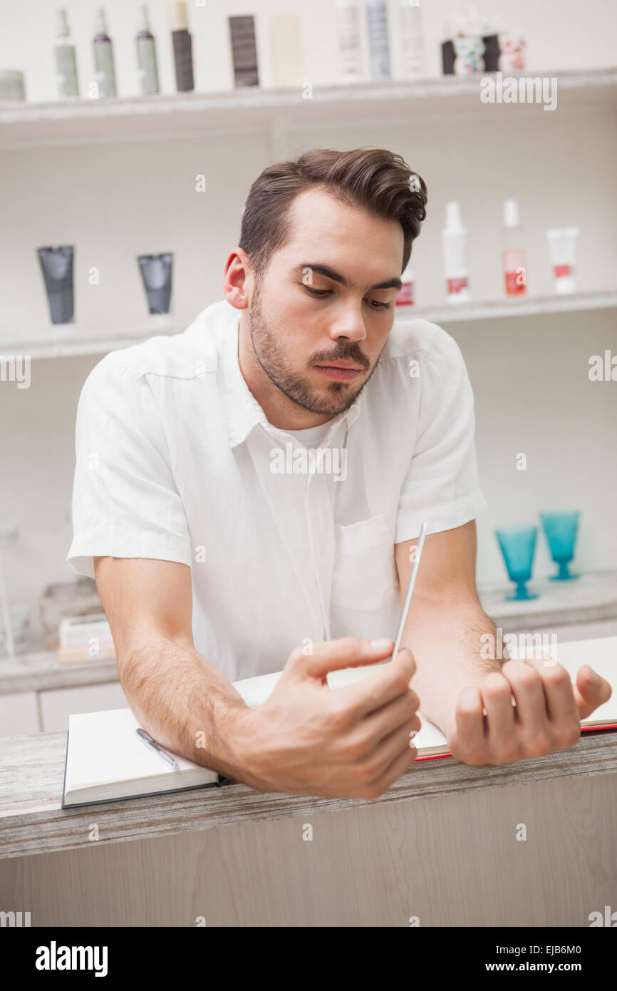 Smiling salon worker with stock book Stock Photo - Alamy