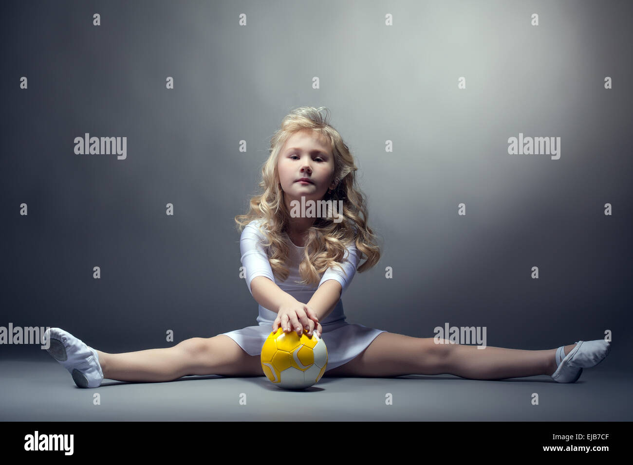 Fascinating little gymnast posing on split Stock Photo - Alamy