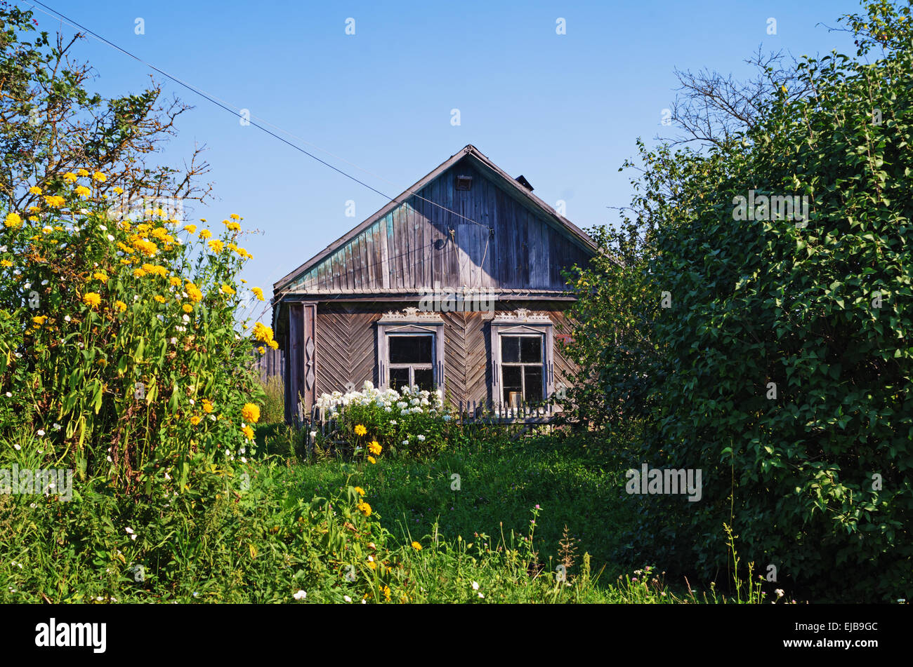 Rural landscape - wooden house front view and yellow flowers bed before ...