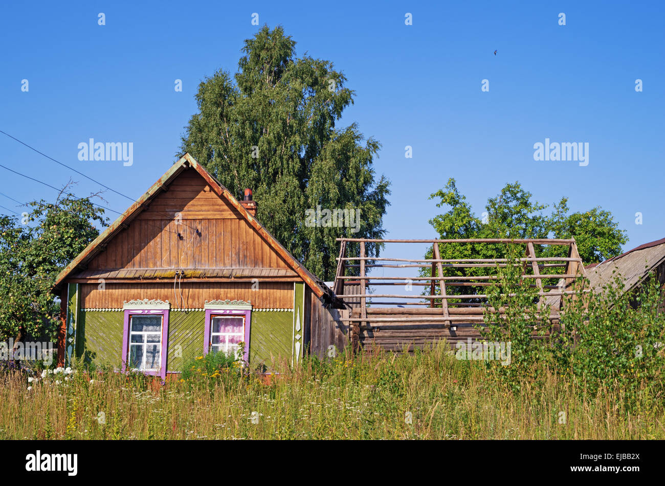 Rural landscape - wooden house, garden and barn with disassembled roof ...