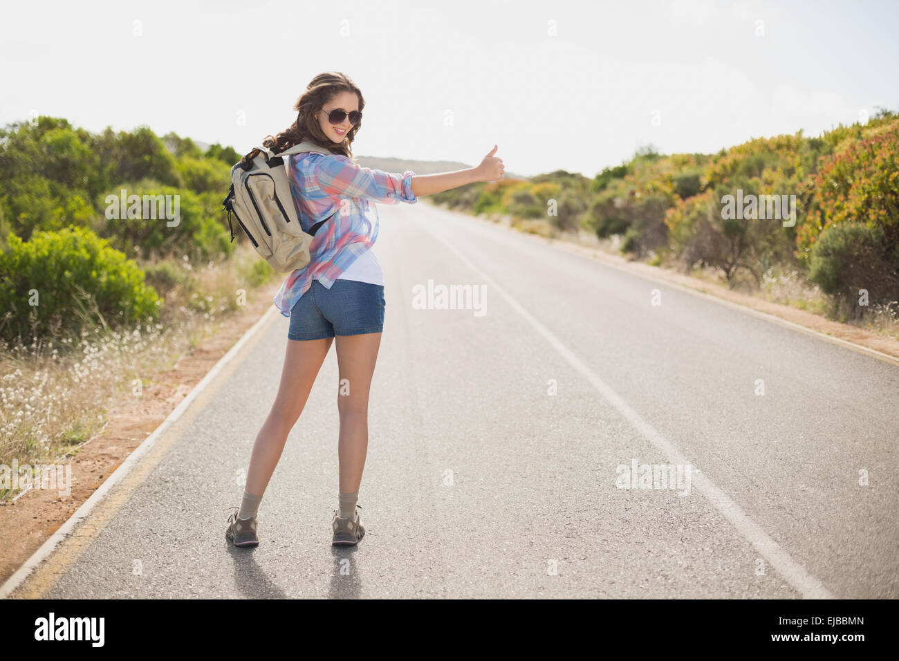 Woman hitchhiking on countryside road Stock Photo - Alamy