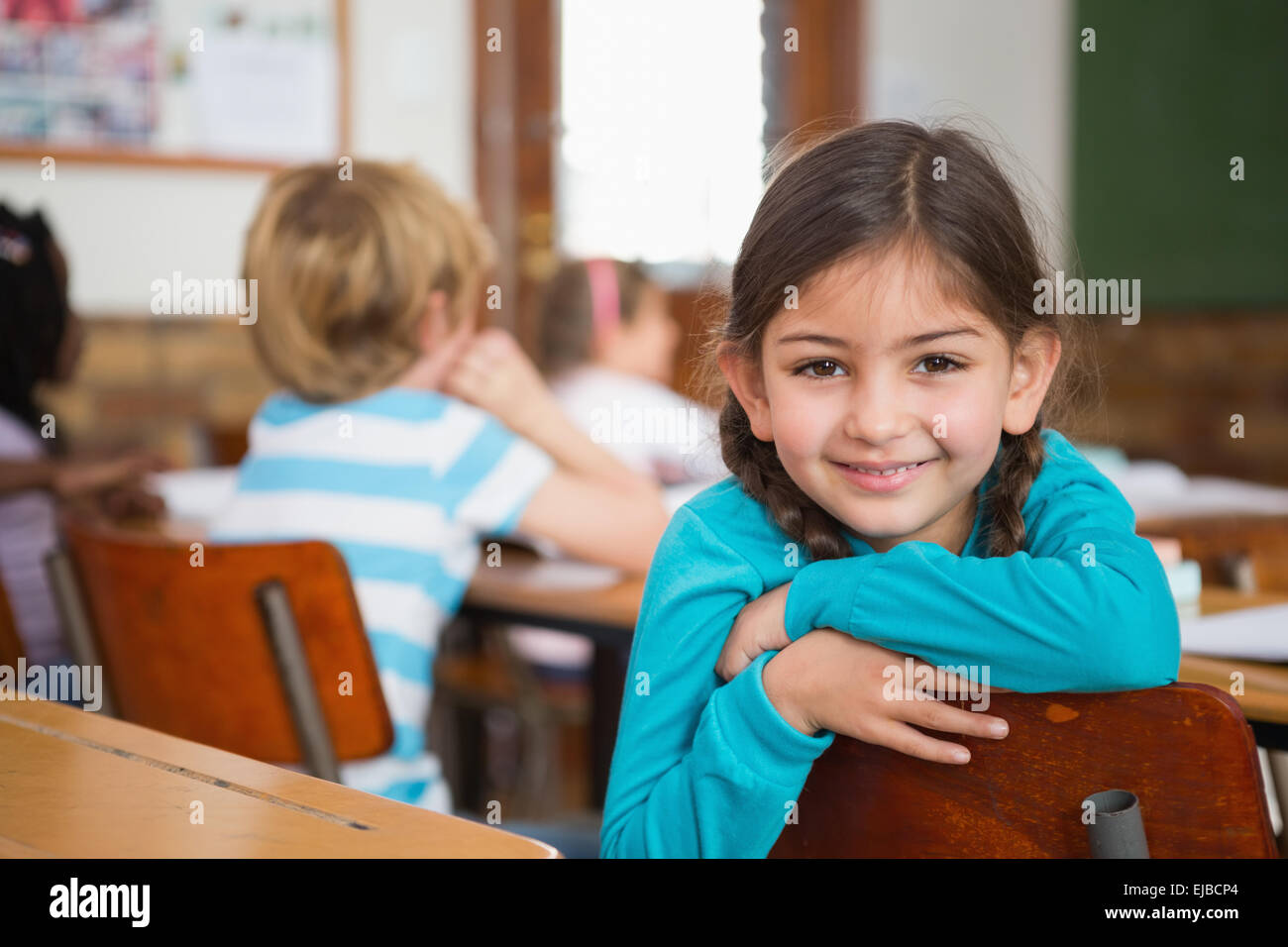 Smiling pupil sitting at her desk Stock Photo - Alamy