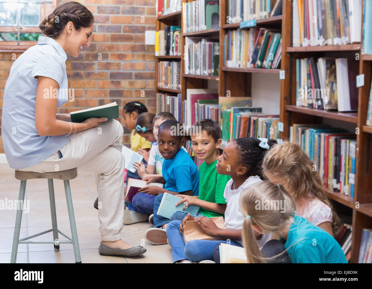 Cute pupils sitting on floor in library Stock Photo - Alamy