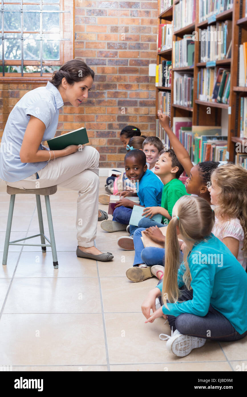Cute pupils sitting on floor in library Stock Photo - Alamy