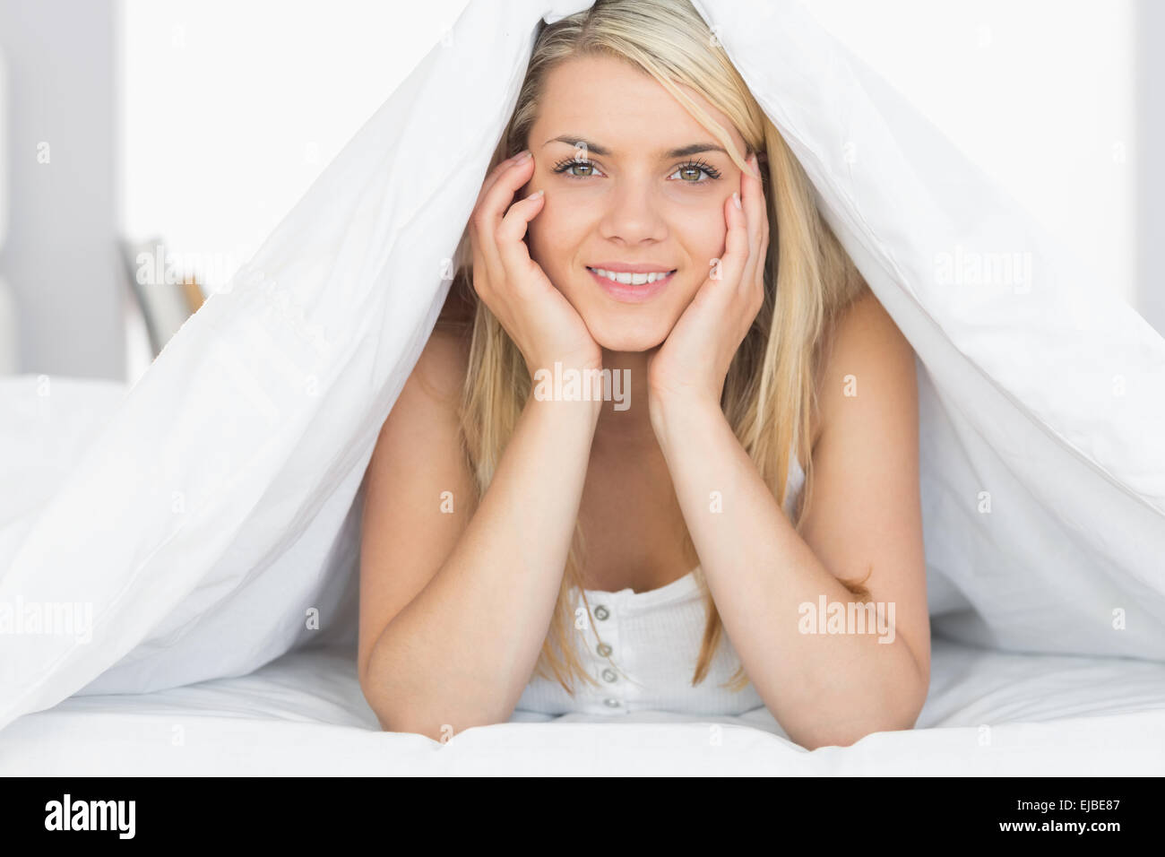 Smiling relaxed young woman lying in bed Stock Photo - Alamy