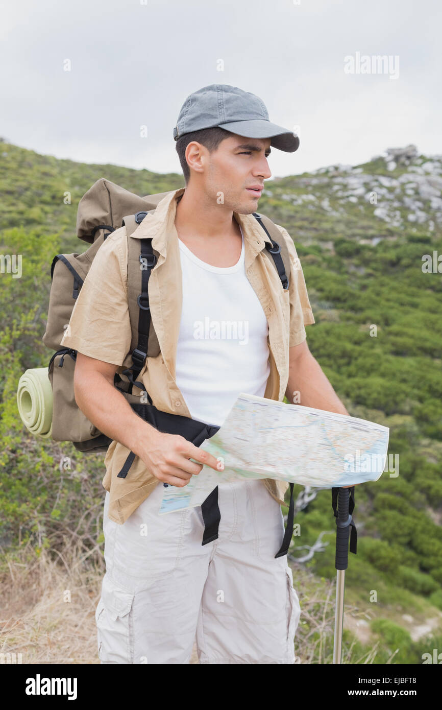 Hiking man holding map on mountain terrain Stock Photo - Alamy