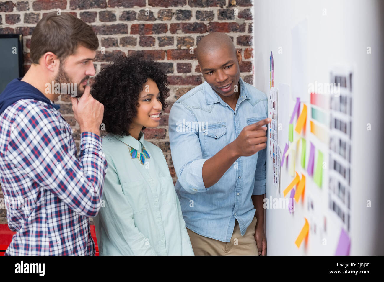 Team looking at sticky notes on wall Stock Photo - Alamy