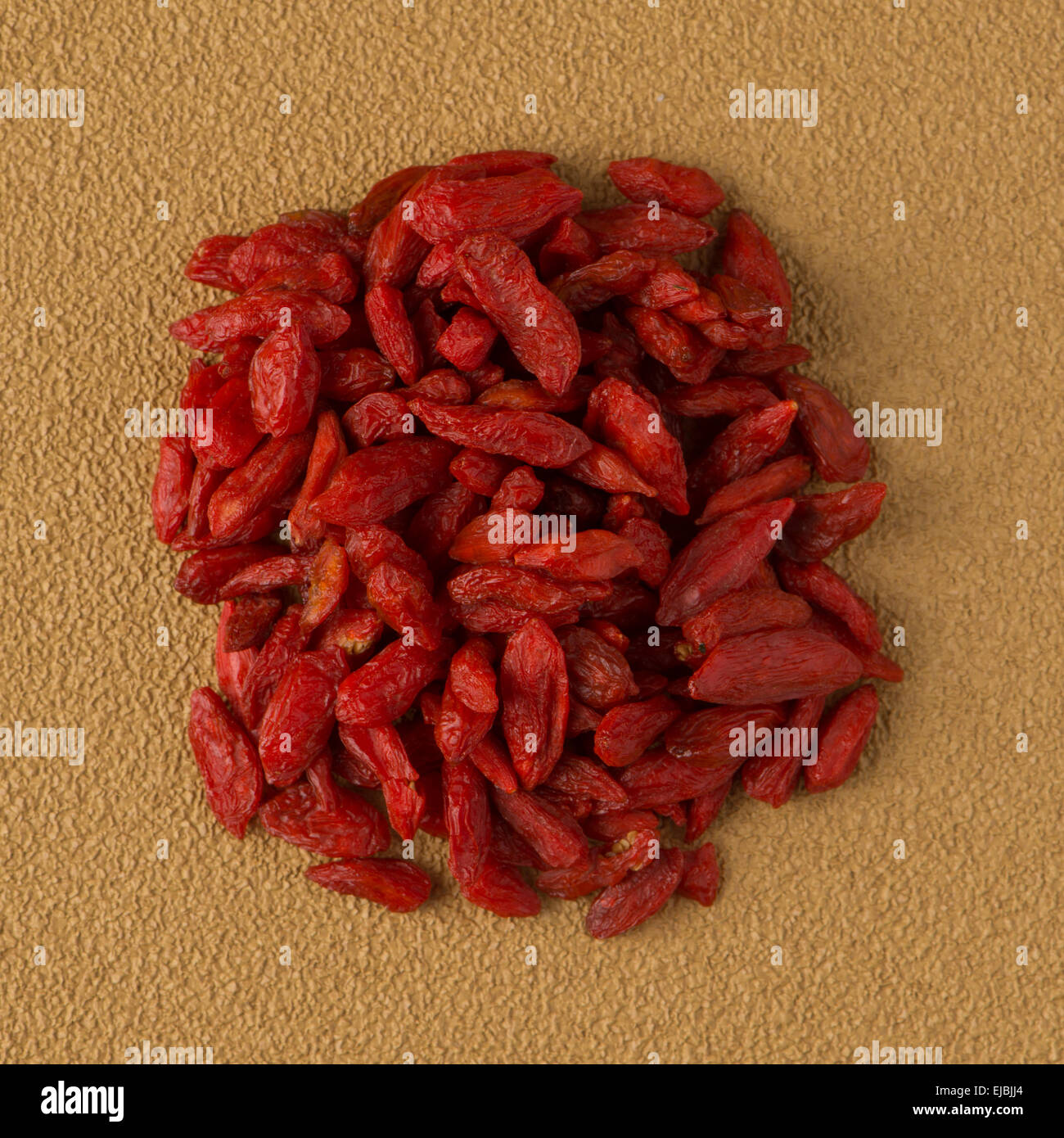 Top view of circle of dry red goji berries against yellow vinyl ...