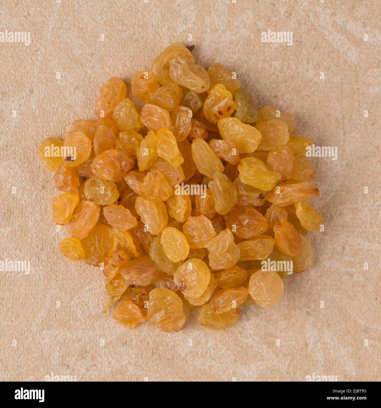 Top view of circle of golden raisins against beige vinyl background ...