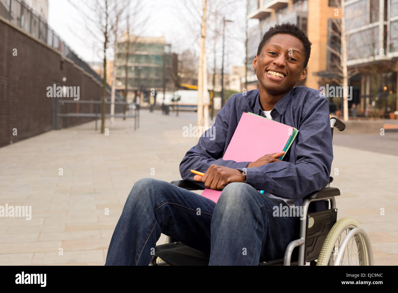 happy young disabled man in a wheelchair holding folders Stock Photo ...