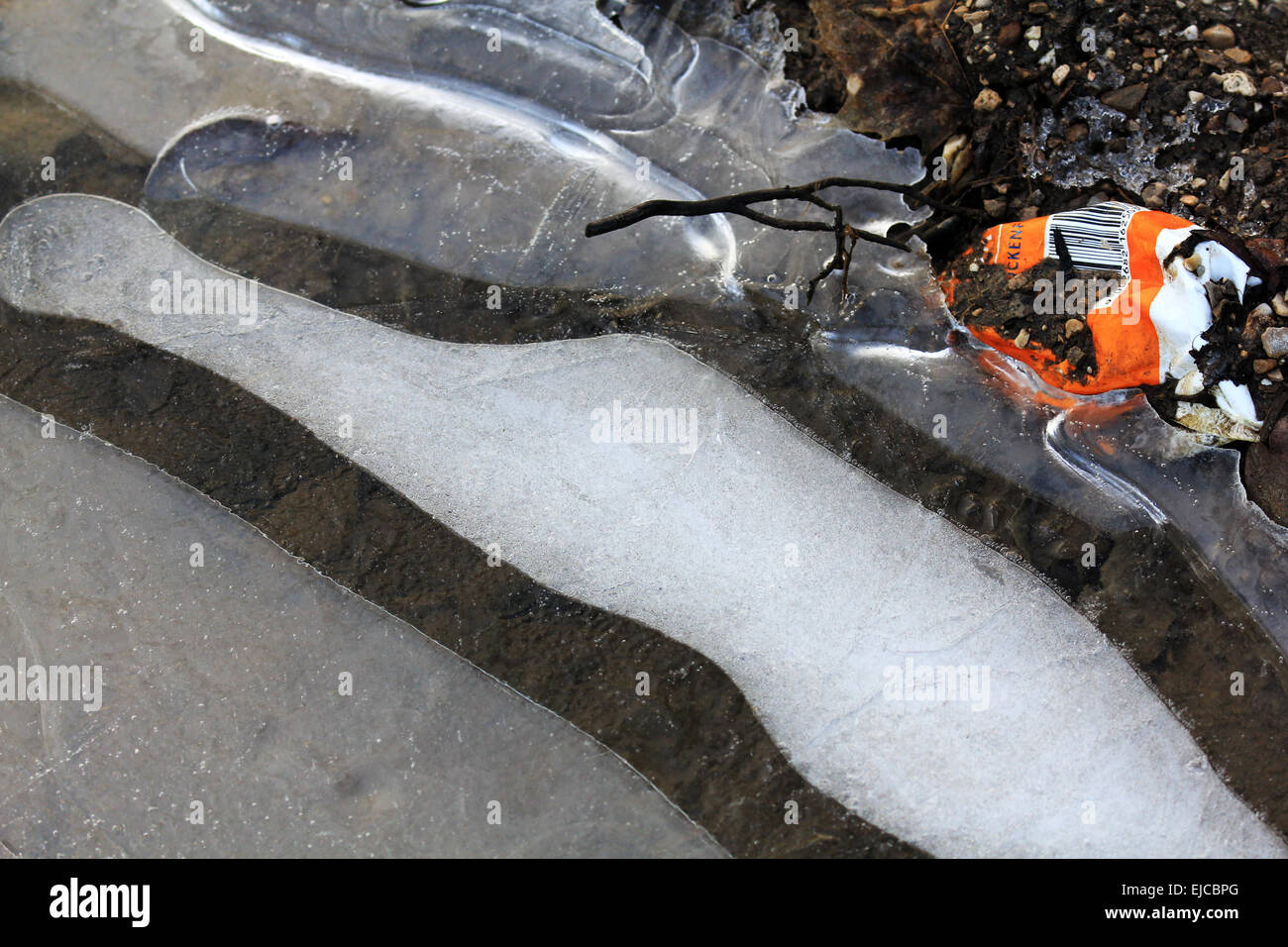 Frozen Puddle with Orange Plastic Stock Photo - Alamy