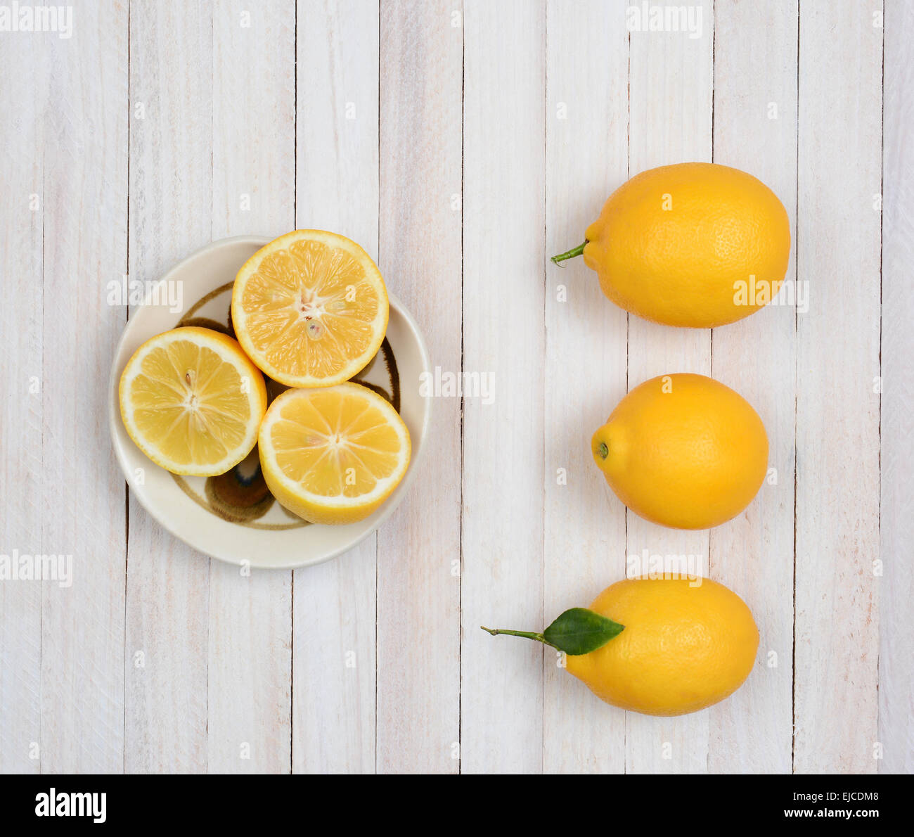 High angle still life of three whole lemons and three lemon halves in a ...
