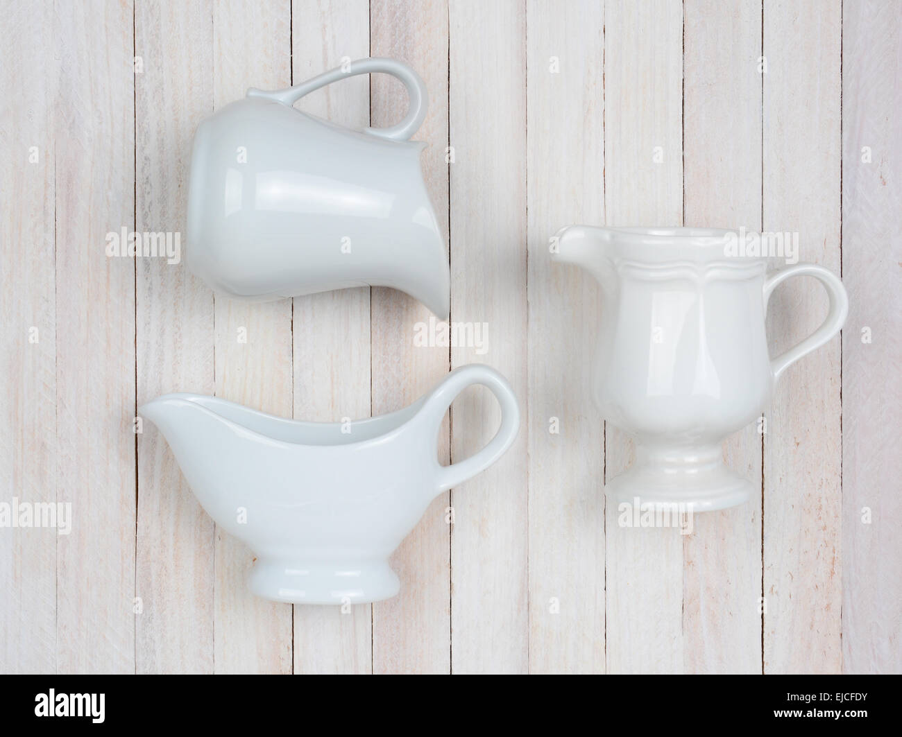 Closeup of three white ceramic pitchers on a rustic whitewashed wood ...