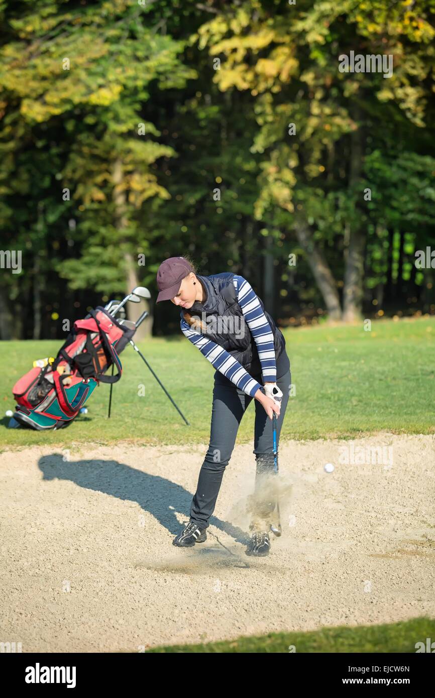 Female golf player put golf ball in sand Stock Photo - Alamy