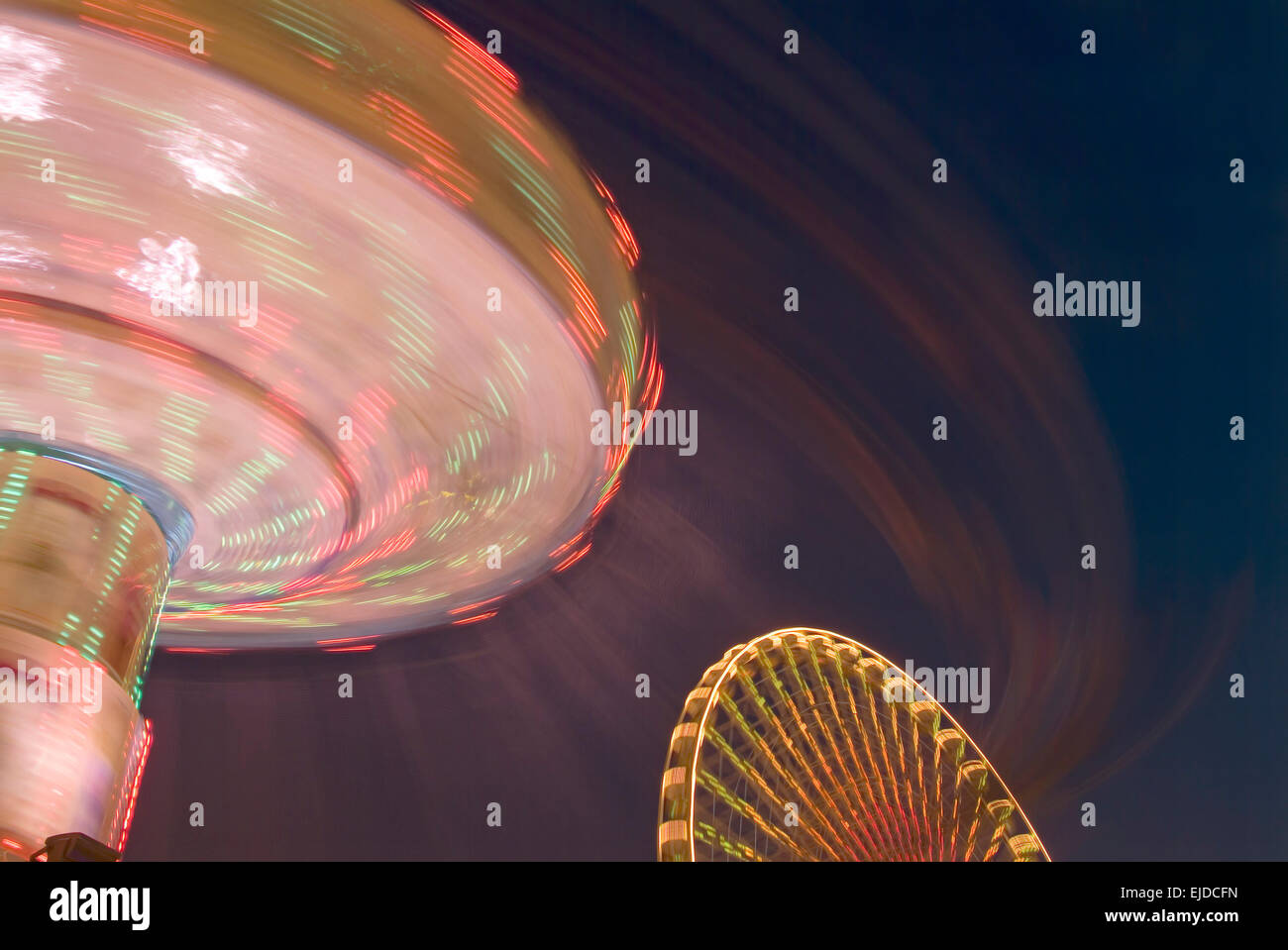 Funfair with giant wheel and merry go round in motion evening light ...