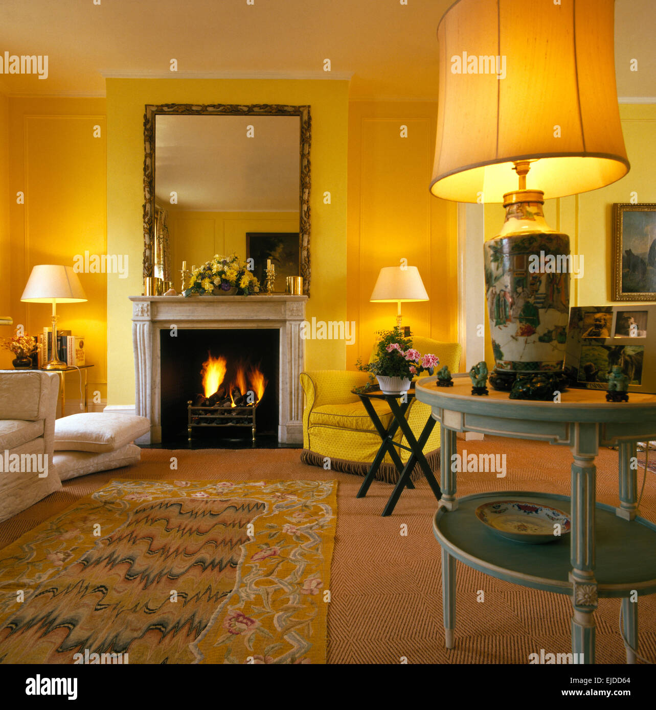 Lighted lamps in yellow nineties living room with large mirror above ...