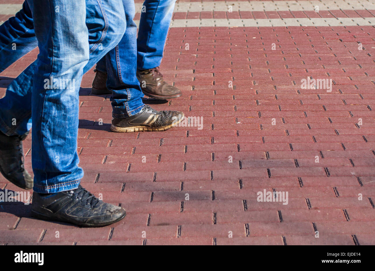 Young Men in blue jeans step forwards together on an urban setting ...
