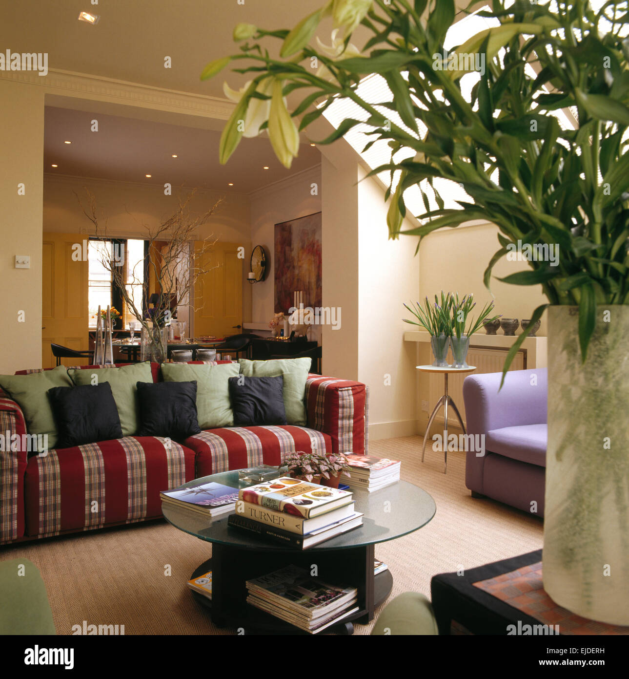 Red patterned sofa piled with cushions in nineties open-plan living and ...