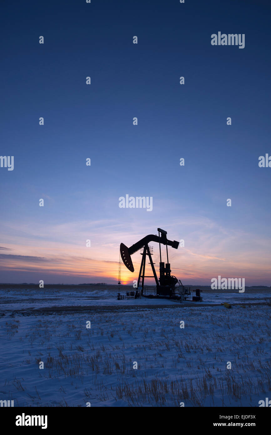 An oil drilling rig and pumpjack on a flat plain in the Canadian oil ...