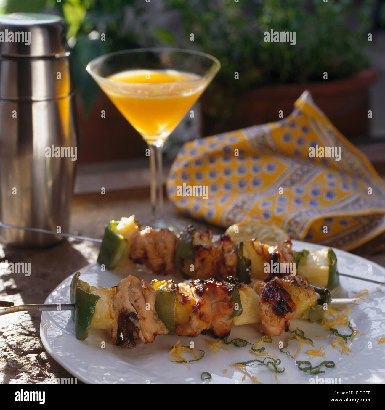 Plate of pork and green pepper kebabs on table with a fruit cocktail ...