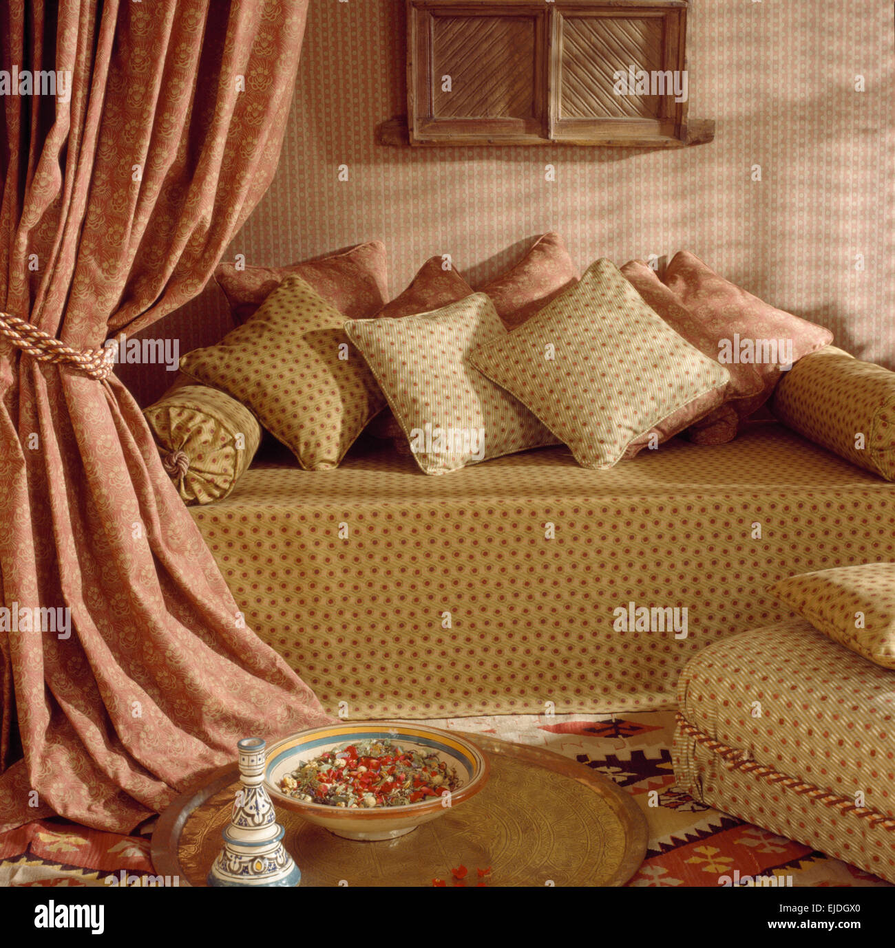 Opulent curtain and cushions on fitted seating in eighties living room ...