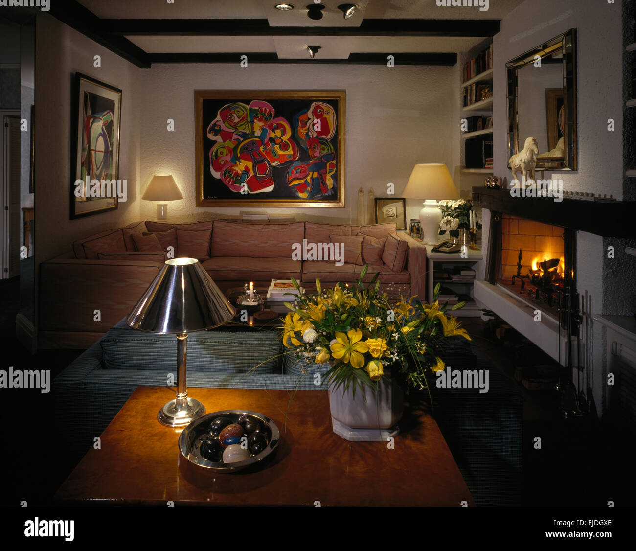 Fireplace with lighted fire in eighties living room with large colorful ...