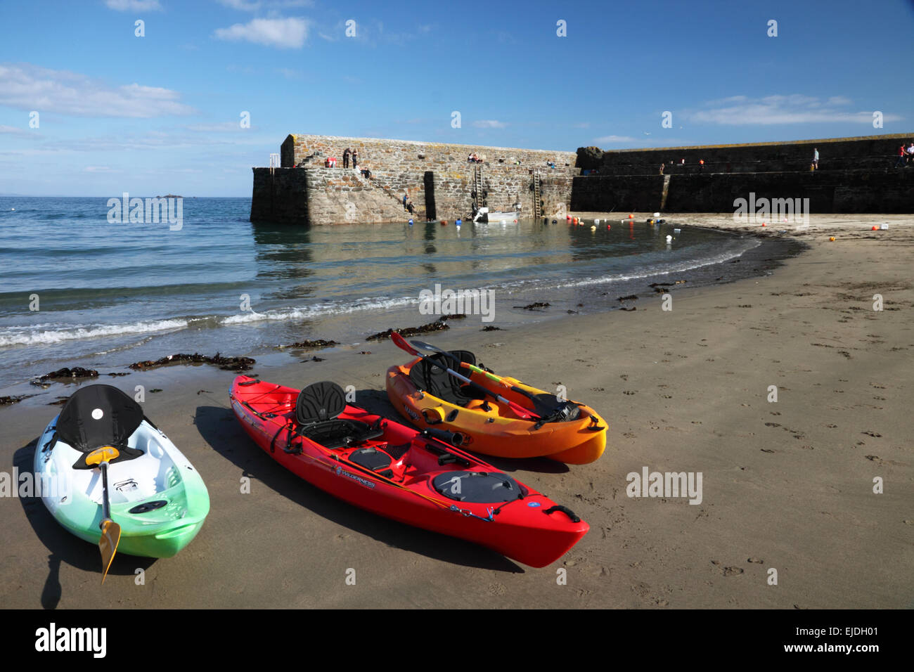 Yellow and red kayaks on a sandy Cornish beach with a stone pier Stock ...