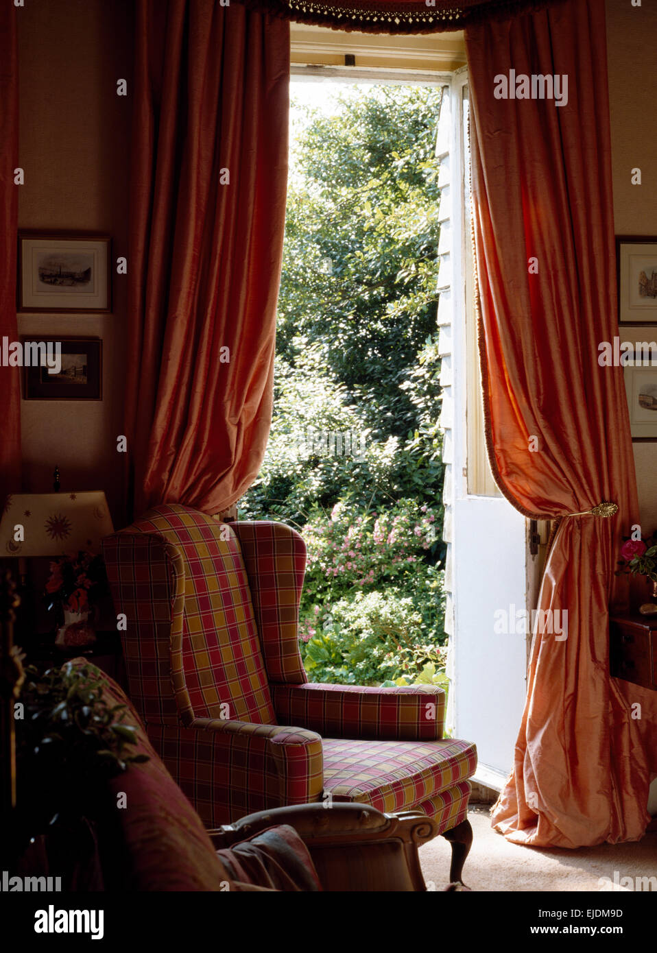 Nineties living room with checked wing chair beside open door with ...