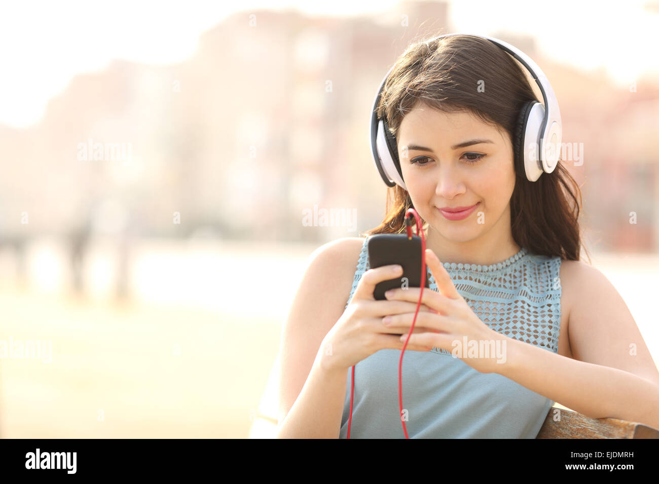 Girl searching songs and listening to the music with headphones in an ...