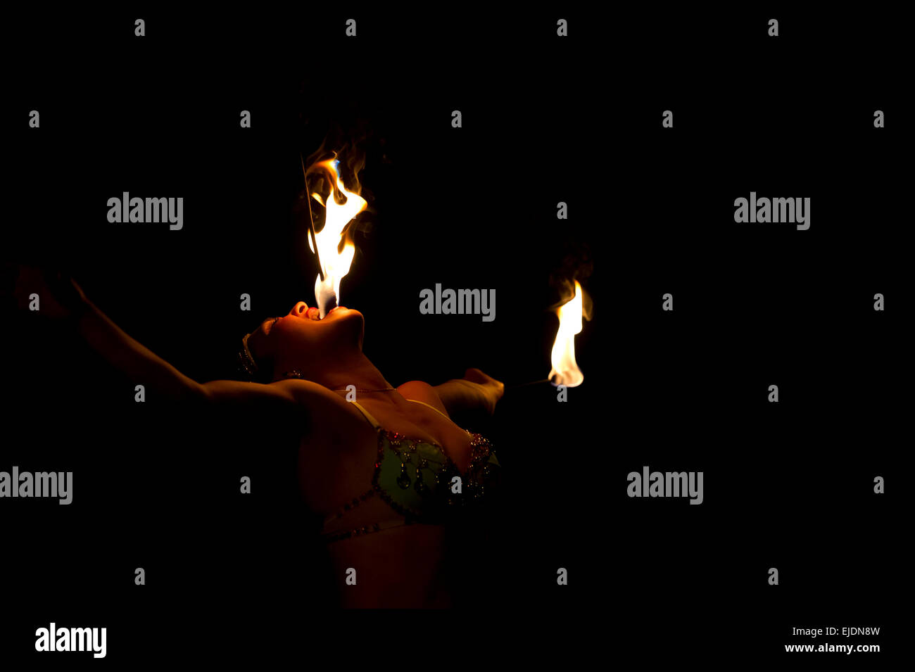 A fire breather woman is eating fire and flames Stock Photo - Alamy