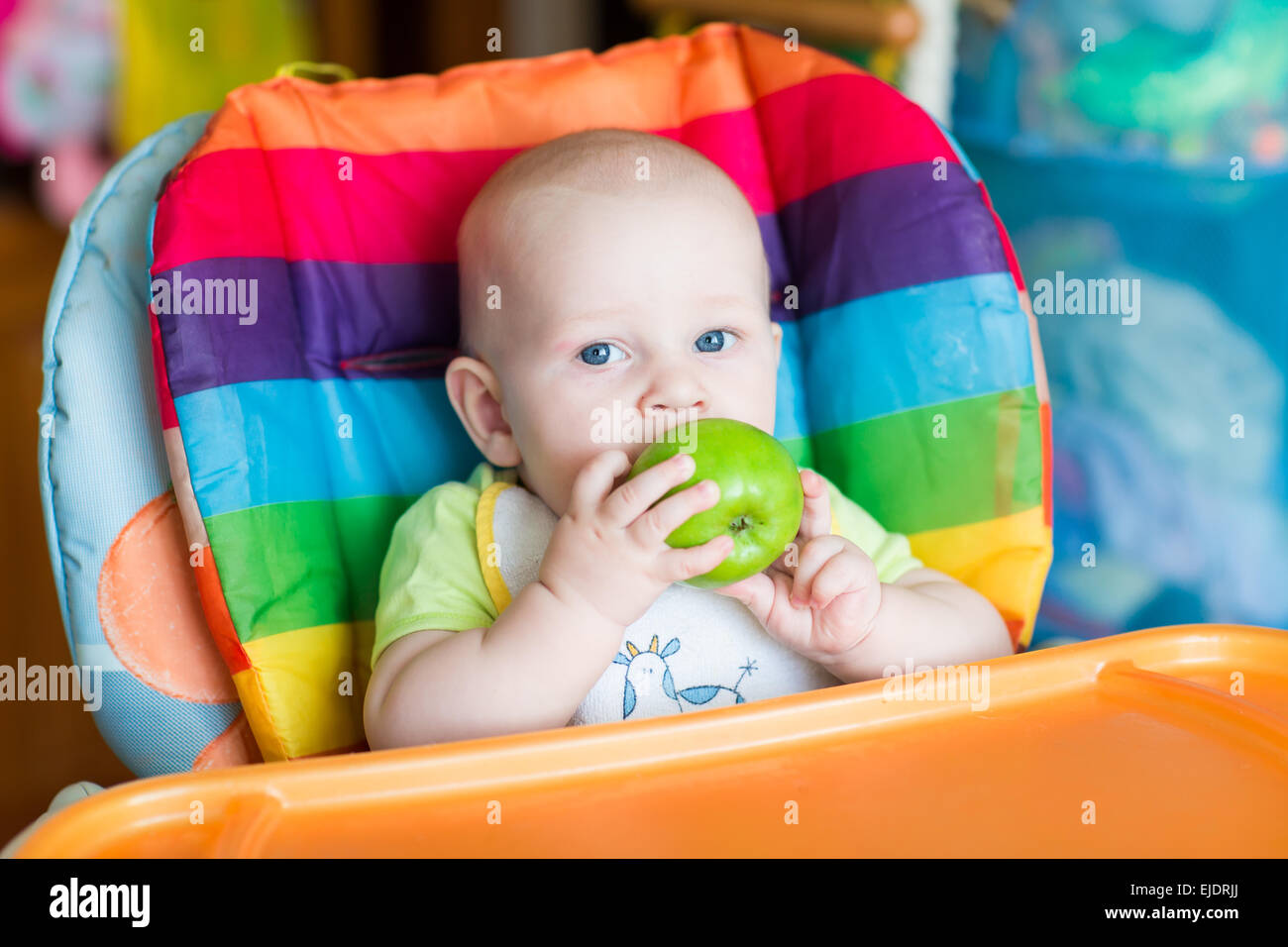 Adorable baby eating apple in high chair. Baby's first solid food Stock ...