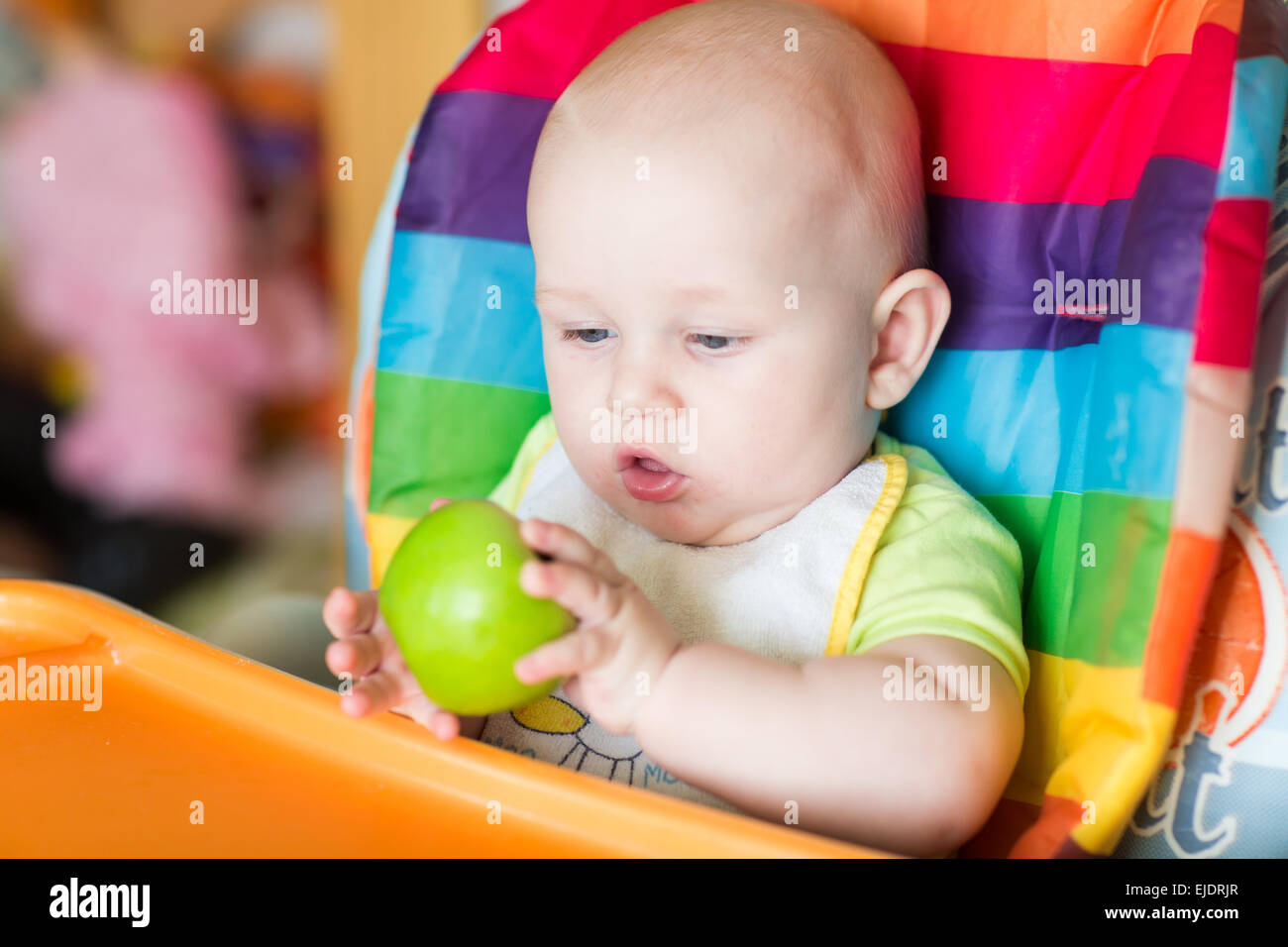 Adorable baby eating apple in high chair. Baby's first solid food Stock ...