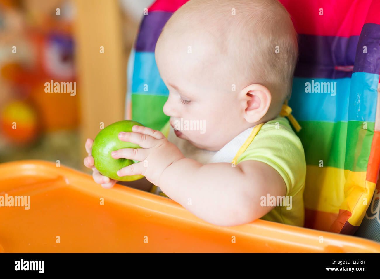Adorable baby eating apple in high chair. Baby's first solid food Stock ...