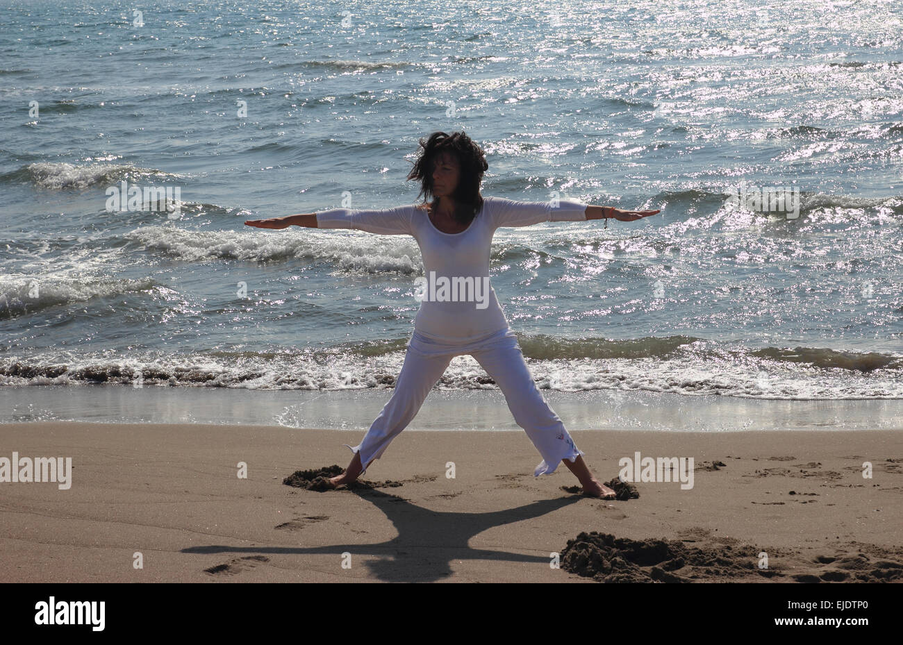 woman doing a standing five pointed star position on a shore Stock ...
