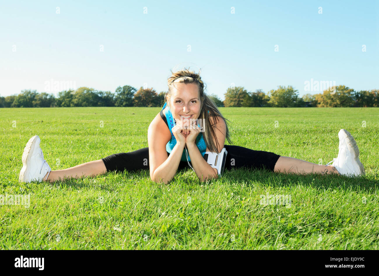 A Woman stretching in a park grass Stock Photo - Alamy