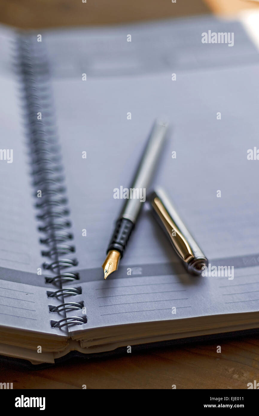 Closeup photo of open notebook with a fountain pen, placed at wood ...