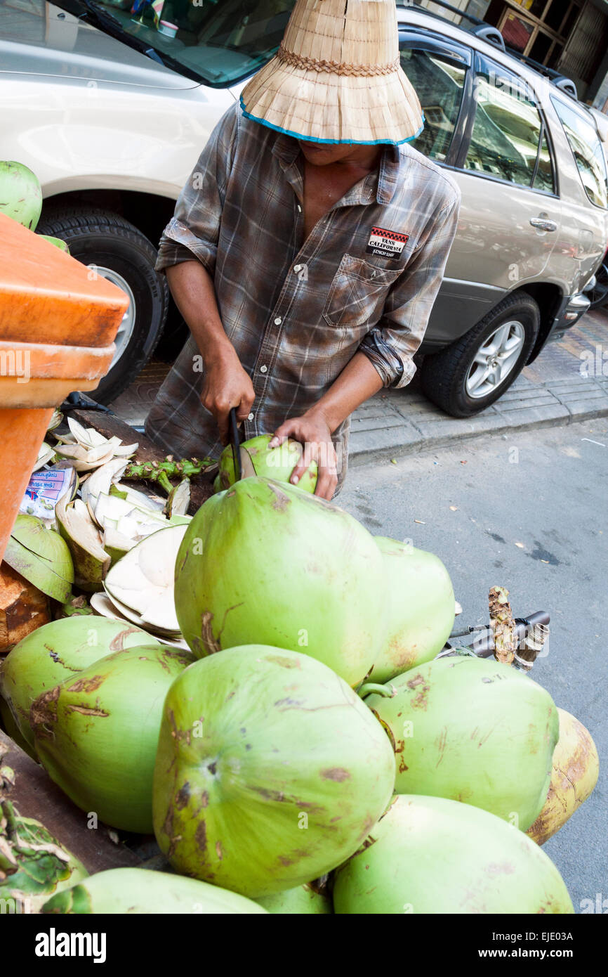 A street vendor selling coconuts on the street in Phnom Penh, Cambodia ...
