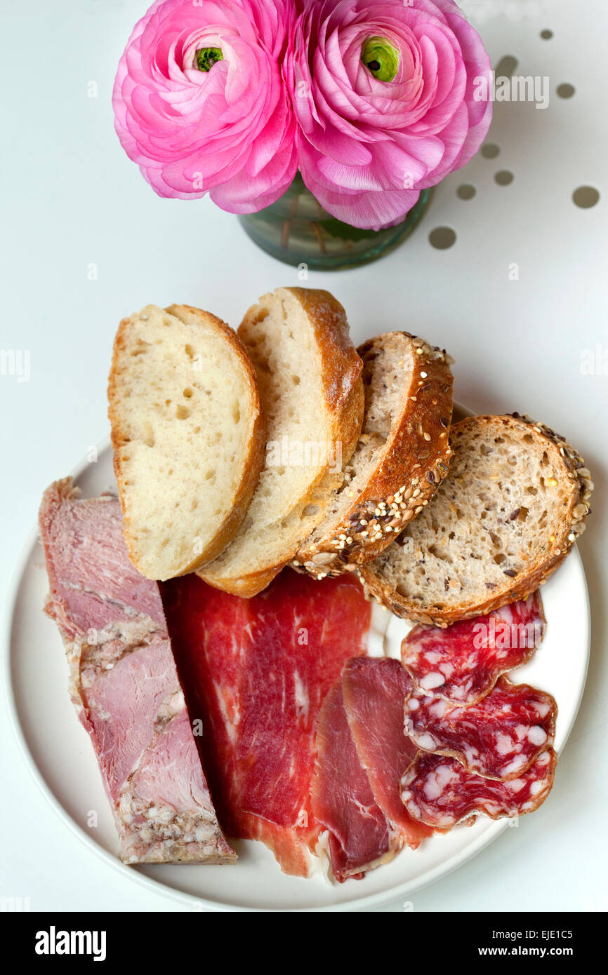 Cold meat, bread and flowers on a table Stock Photo - Alamy