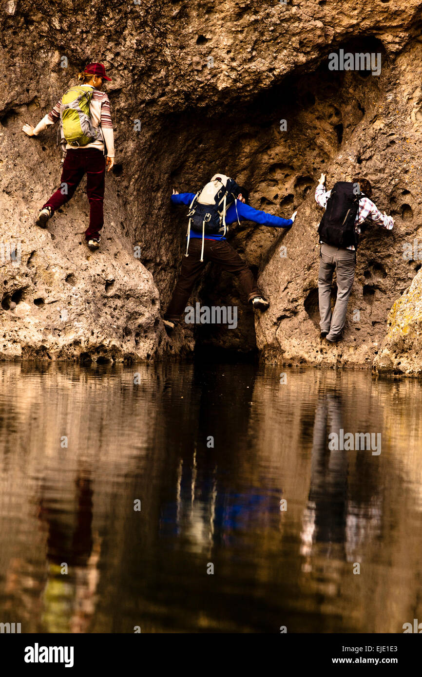 Three males climbers work their way across the Rock Pool traverse at ...