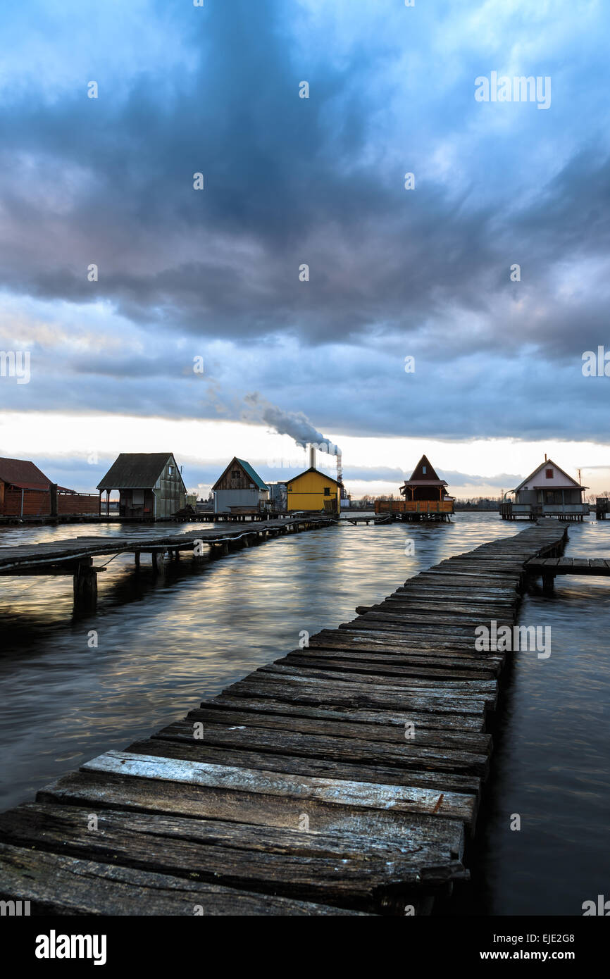 Sunset lake Bokod with pier and fishing wooden cottages, power plant in ...