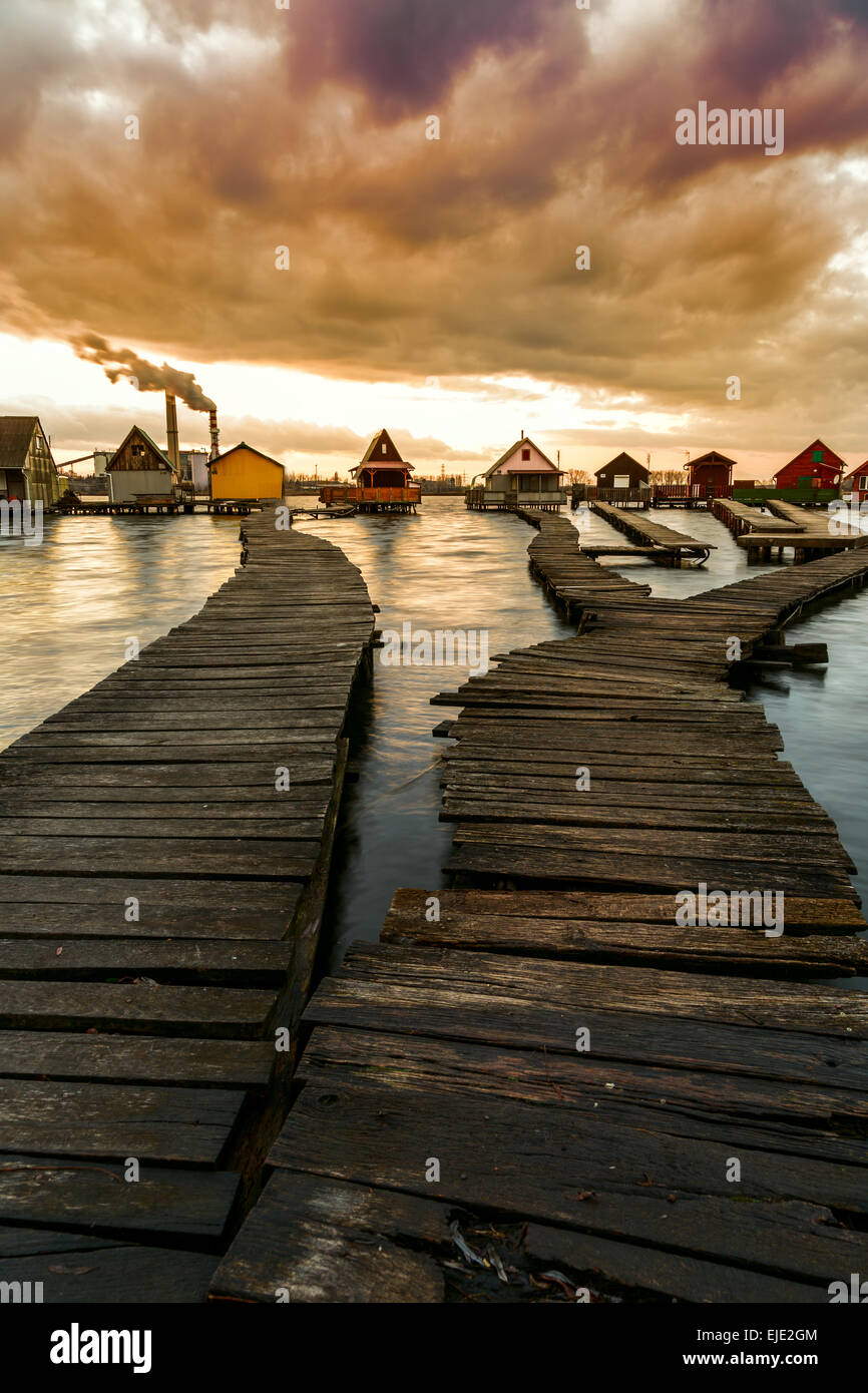 Sunset lake Bokod with pier and fishing wooden cottages, power plant in ...