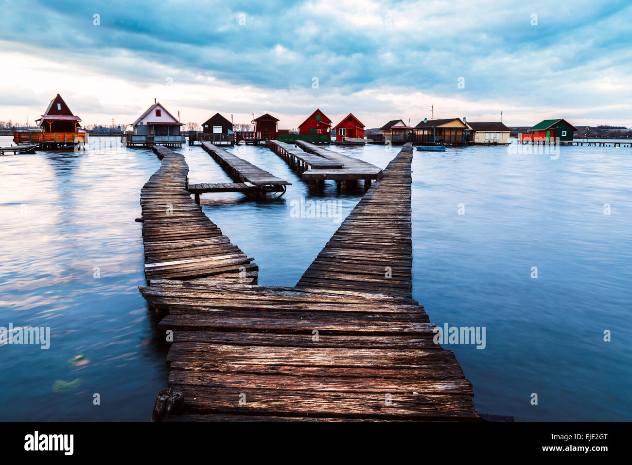 Sunset lake Bokod with pier and fishing wooden cottages, power plant in ...