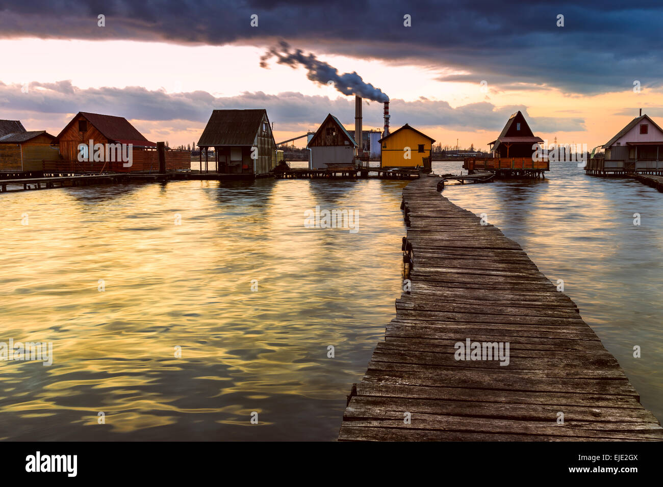 Sunset lake Bokod with pier and fishing wooden cottages, power plant in ...
